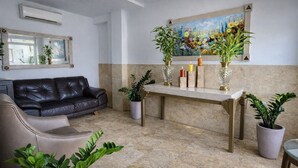 Uma sala de estar com sofá de couro, uma mesa de centro com velas e plantas em vasos.