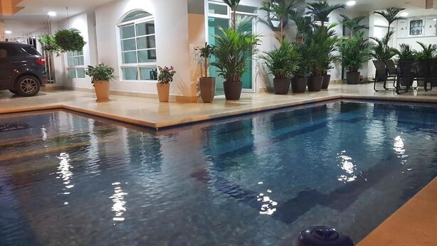 Piscina interna com plantas em vasos e um carro estacionado do lado de fora.