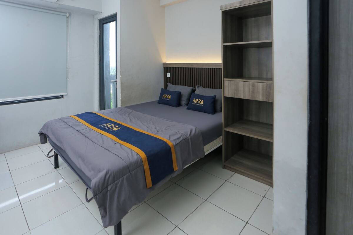 Quarto moderno com cama, duas almofadas, encosto e estante embutida.