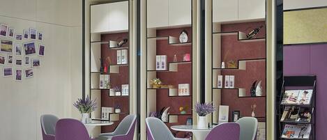 Um interior moderno com uma mesa redonda e quatro cadeiras, uma estante com diversos objetos e uma parede com fotografias.