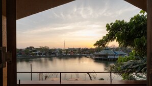 Vista de uma varanda com vista para um corpo d'água calmo e edifícios ao fundo.