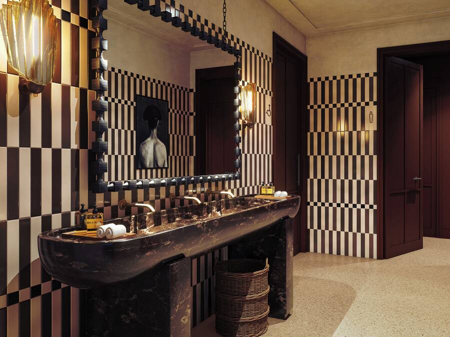 Casa de banho com lavatório de mármore preto, um espelho grande e padrão de parede quadriculado.