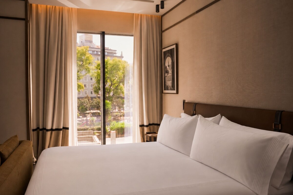 Quarto de hotel com cama grande, vista para o exterior e quadro decorativo na parede.