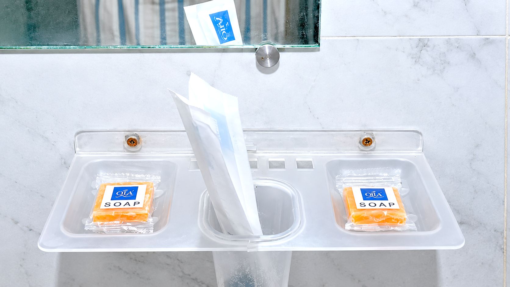 Uma pia de banheiro com dois dispensadores de sabonete e um suporte para toalhas de papel.