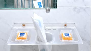 Uma pia de banheiro com dois dispensadores de sabonete e um suporte para toalhas de papel.