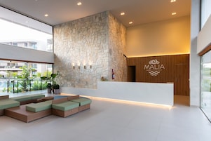 Uma área de recepção moderna com parede de pedra, balcão de madeira e espaço de estar com almofadas.