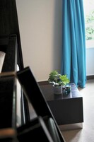 Quarto moderno com uma mesa de cabeceira preta, uma planta em vaso e um copo.
