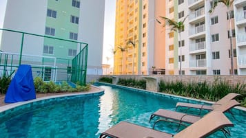 Piscina com espreguiçadeiras, cercada por edifícios altos.