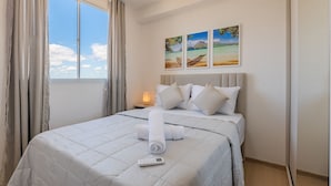 Quarto de hotel com cama, controle remoto e janela com cortinas.