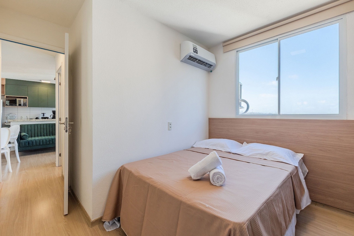 Quarto de hotel com cama, janela e ar condicionado.