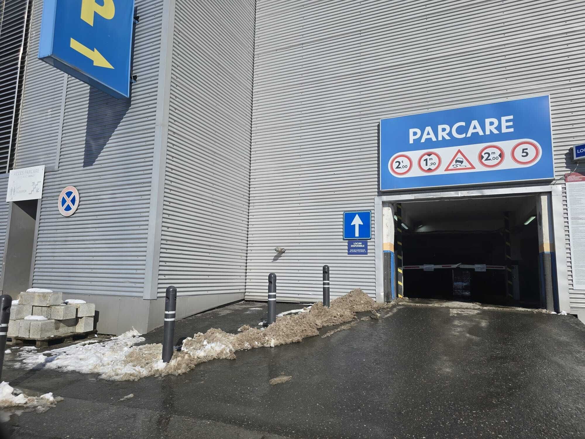 Entrada de estacionamento com um letreiro indicando "PARCARE" e uma placa azul apontando a direção para a área de estacionamento.
