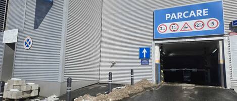 Entrada de estacionamento com um letreiro indicando "PARCARE" e uma placa azul apontando a direção para a área de estacionamento.
