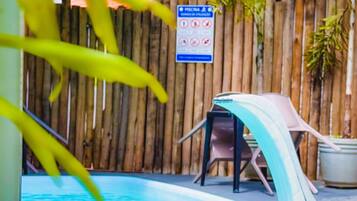 Piscina com cerca de madeira, uma cadeira e uma placa com símbolos.