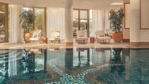 Uma piscina com piso ladrilhado e espreguiçadeiras.