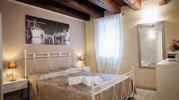 Quarto com cama, luminárias de cabeceira, um espelho e um quadro na parede.
