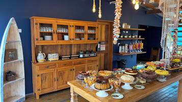 Buffet de madeira com diversos doces e aparador de madeira com copos.