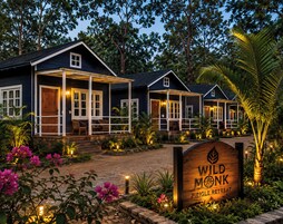 Cabanas com varanda e área de estar externa, cercadas por vegetação exuberante e uma placa indicando um refúgio na selva.