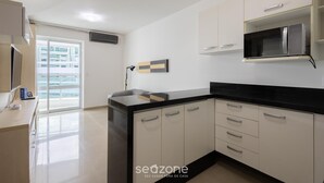 Cozinha moderna com armários brancos, bancada preta e micro-ondas.