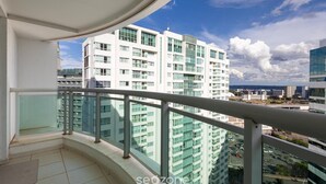 Varanda com guarda-corpo de vidro e vista para um complexo moderno de edifícios.