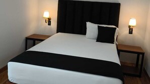 Quarto com uma cama grande, duas mesas de cabeceira, um ventilador de teto e um ar condicionado.