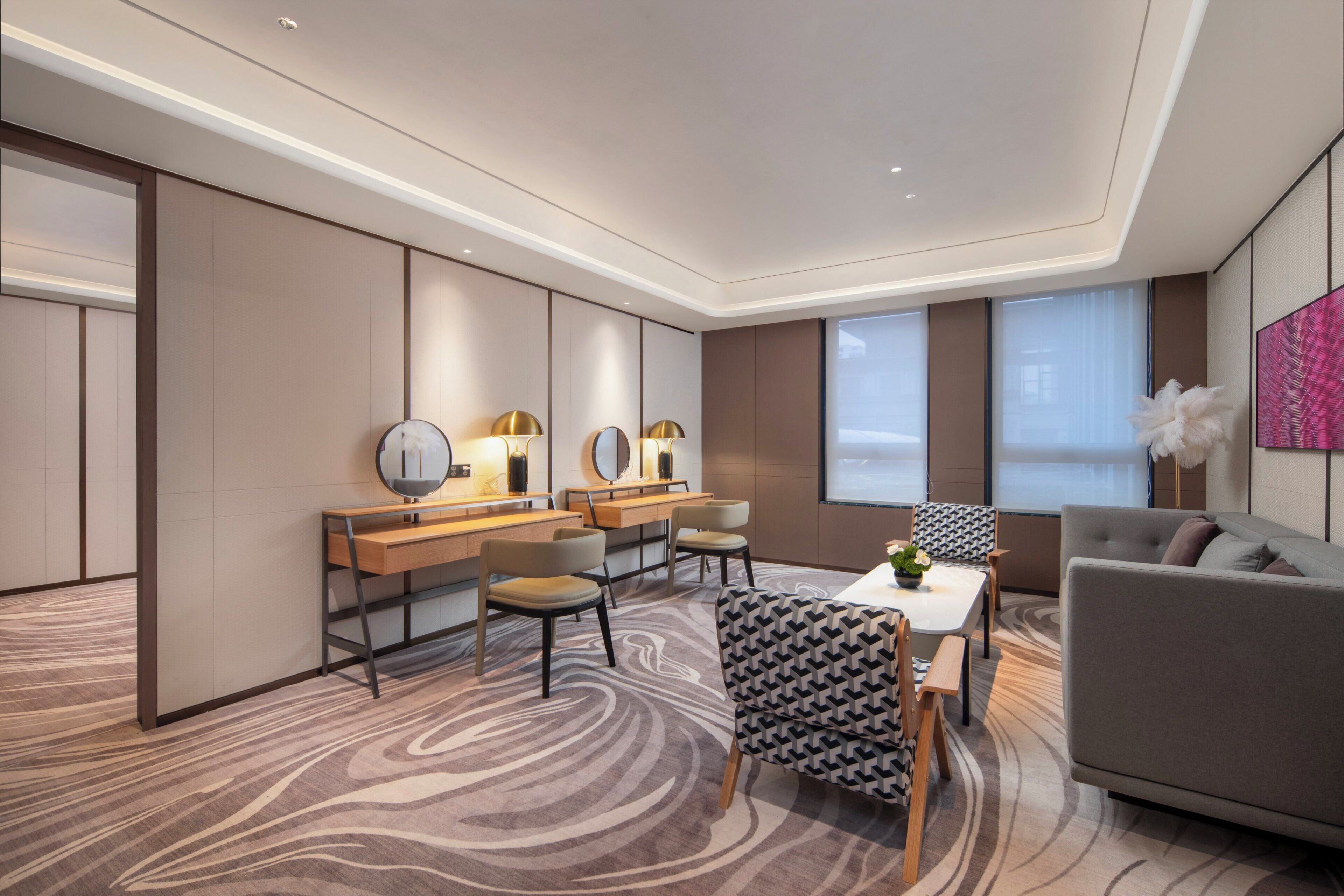Quarto de hotel moderno com área de refeições, sofá e uma janela grande.
