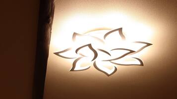 Uma parede com luminária projetando a sombra de uma flor de lótus.