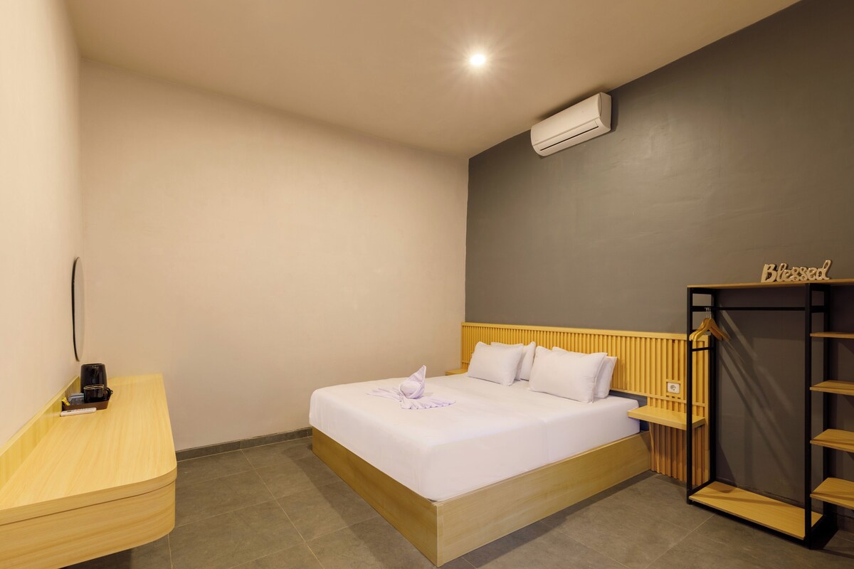 Quarto de hotel com cama, mesa de cabeceira e estante.