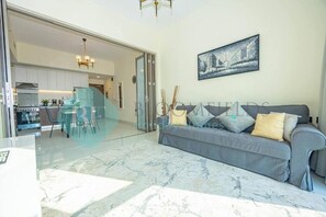 Uma sala de estar moderna com um sofá cinzento, piso de mármore e uma pintura da paisagem urbana na parede.