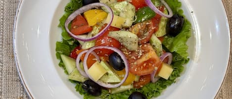 Prato branco com salada sobre fundo de tecido texturizado.