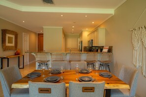 Uma sala de jantar com mesa de madeira posta para seis pessoas, rodeada por seis cadeiras.