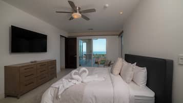 Quarto moderno com cama grande, ventilador de teto, TV de tela plana e vista para o exterior.