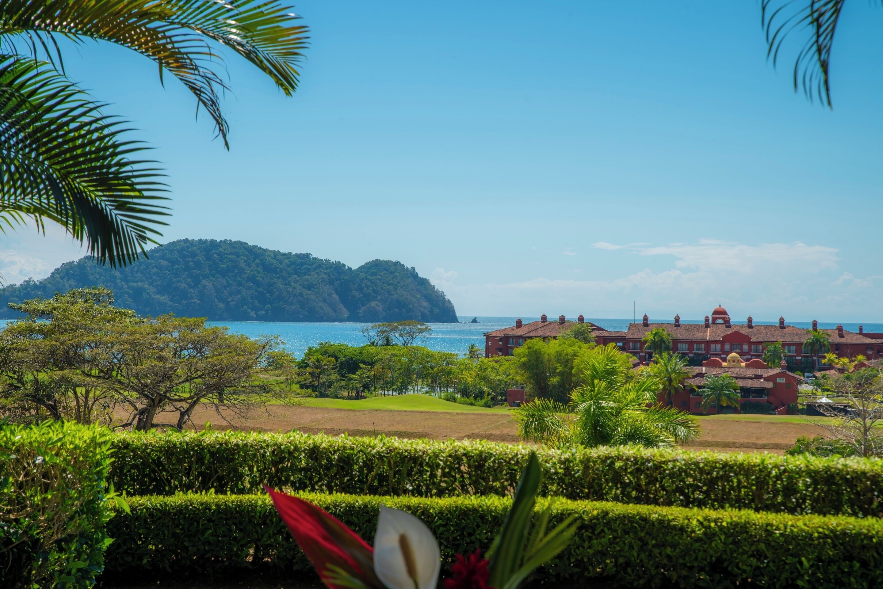 Paisagem costeira com vista para o mar, uma colina e um conjunto de edifícios.