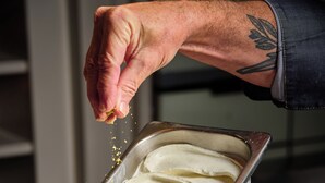 Uma mão espalhando algo sobre uma bandeja de sorvete.