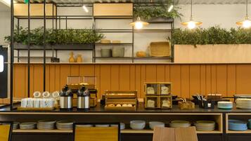 Interior de restaurante com balcão, prateleiras com cestos e plantas pendentes.