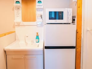 Uma cozinha compacta com micro-ondas, pia e um pequeno armário.