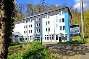 Um hotel com design moderno, exibindo uma placa grande com a palavra 'HOTEL', uma área de recepção e uma placa de estacionamento.