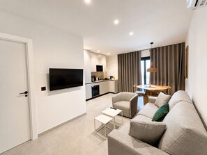 Uma sala de estar moderna com um sofá, uma mesa de centro e uma televisão fixada na parede.