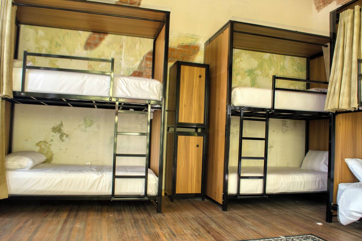 Quarto estilo dormitório com beliches, paredes de madeira e um guarda-roupa pequeno.