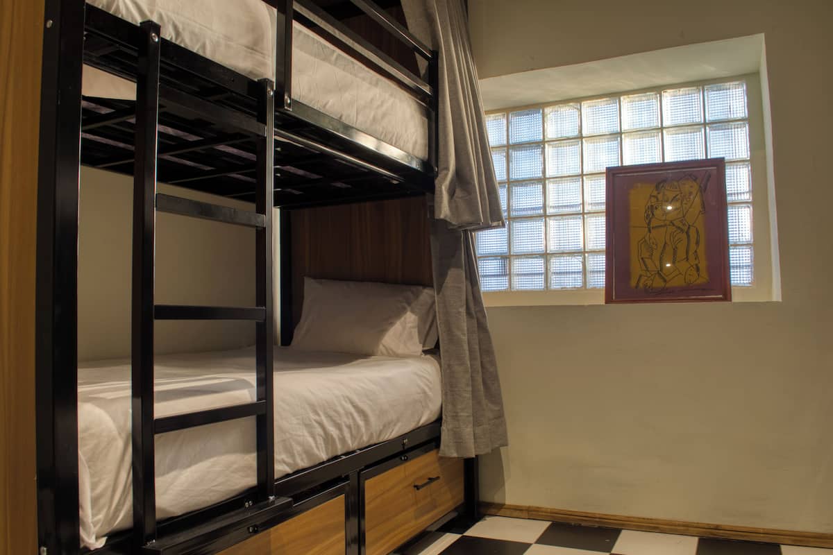 Uma cama de beliche com uma janela e uma obra de arte emoldurada na parede.
