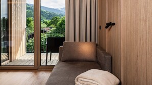 Quarto moderno com uma grande porta de vidro deslizante para uma varanda, um sofá com um cobertor dobrado e uma parede de madeira.