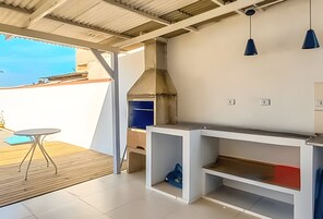 Uma cozinha moderna com armários brancos, fogão embutido e iluminação pendente.