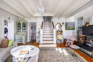 Uma sala de estar espaçosa com escada, lareira e área de refeições.