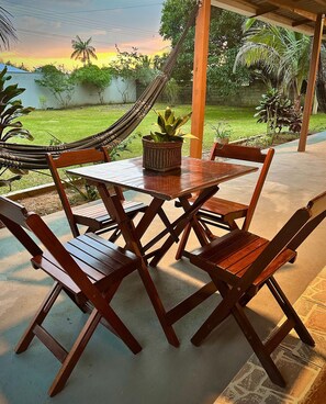 Conjunto de jantar de madeira para área externa, incluindo mesa, cadeiras, uma rede e um vaso de planta.