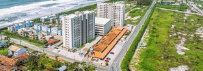Vista aérea de uma área urbana costeira com edifícios altos, uma praia e uma estrada.