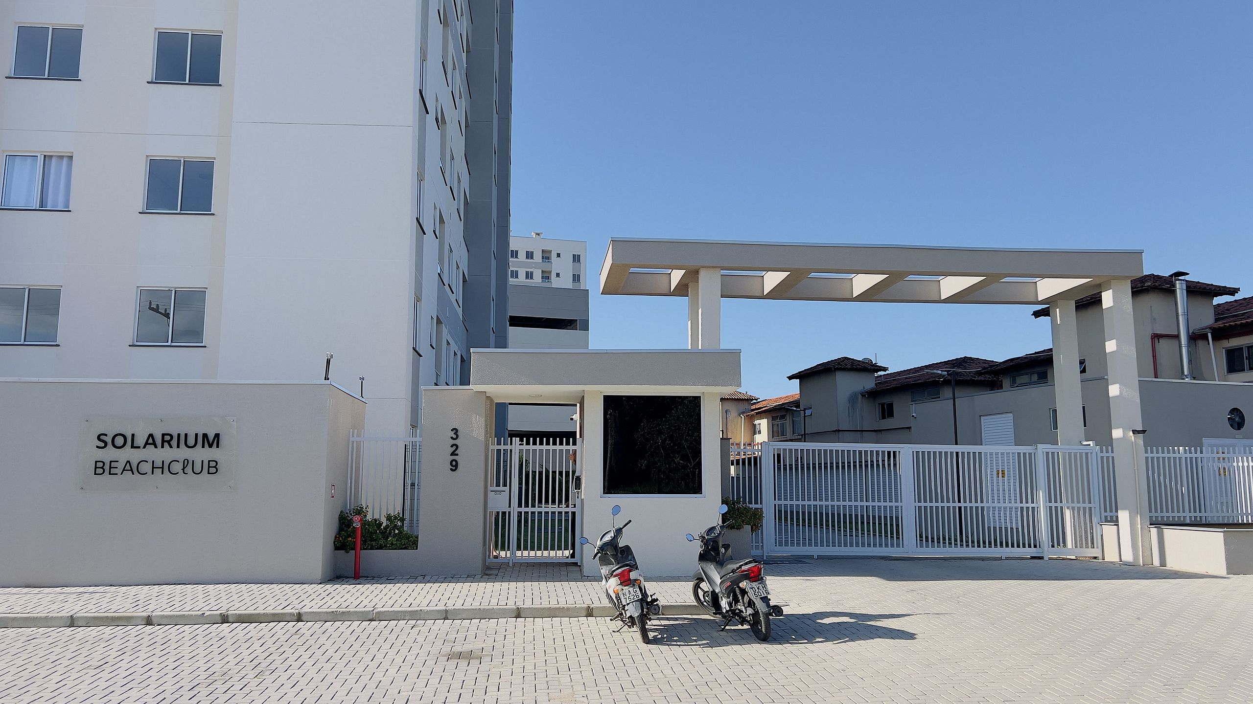 Um edifício com uma placa indicando 'SOLARIUM BEACH CLUB' e uma entrada fechada por portão.