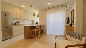 Uma cozinha moderna com uma ilha central, cadeiras de madeira e um espaço de refeições com um sofá estampado.