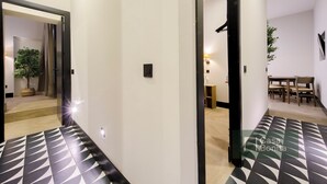Um interior moderno com piso estampado em padrão geométrico, uma sala de jantar com móveis de madeira e um vaso de planta.