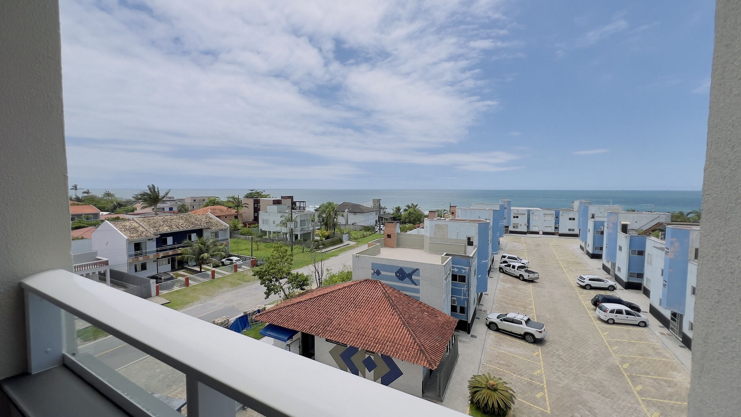 Zona residencial com vista para o mar, com edifícios modernos, um estacionamento e varandas.