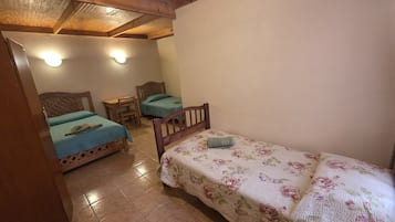 Quarto com duas camas, teto de madeira e chão de azulejos.