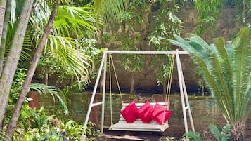 Uma cadeira balanço com almofadas vermelhas em um jardim exuberante.